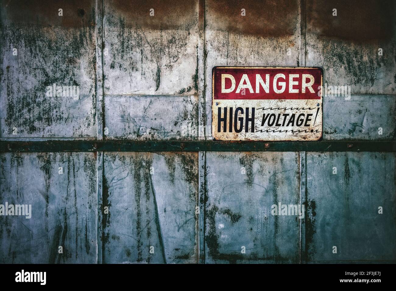 A closeup of a sign with "DANGER HIGH VOLTAGE" on a grungy rusty ...