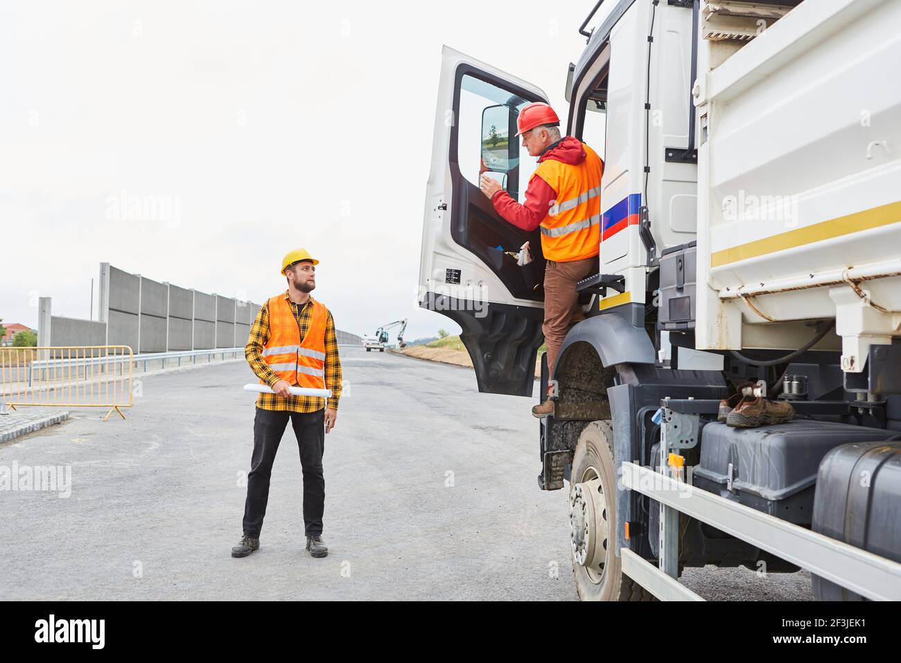 Truck driver talks to construction workers on the construction site of ...