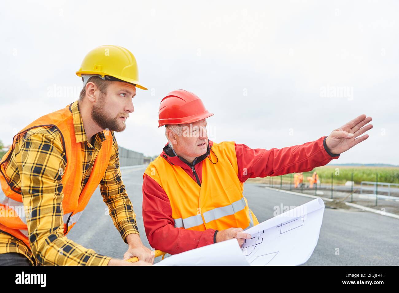 Site manager and foreman with plan for development on construction site ...