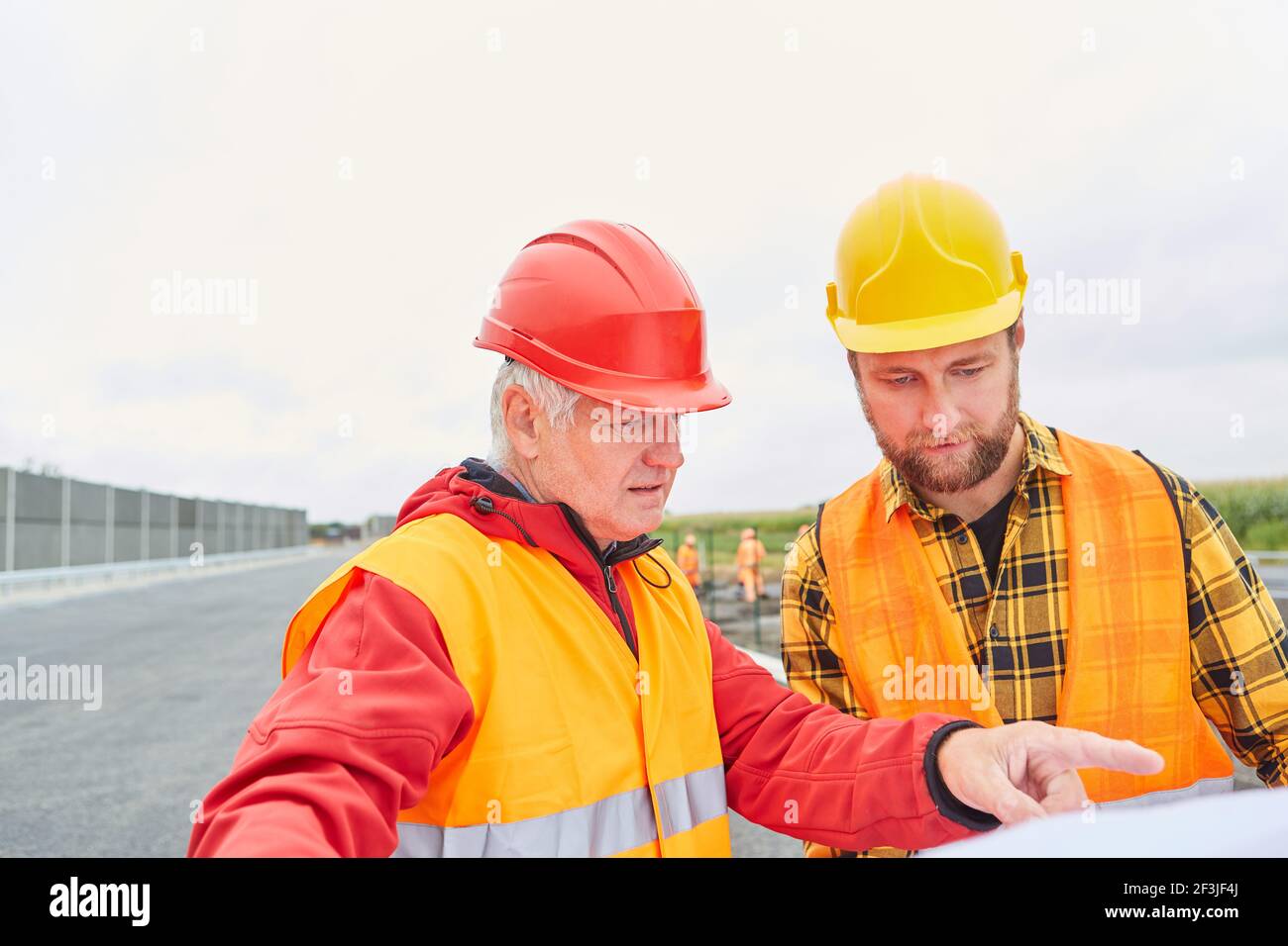 Architect and construction worker with architectural drawing when ...