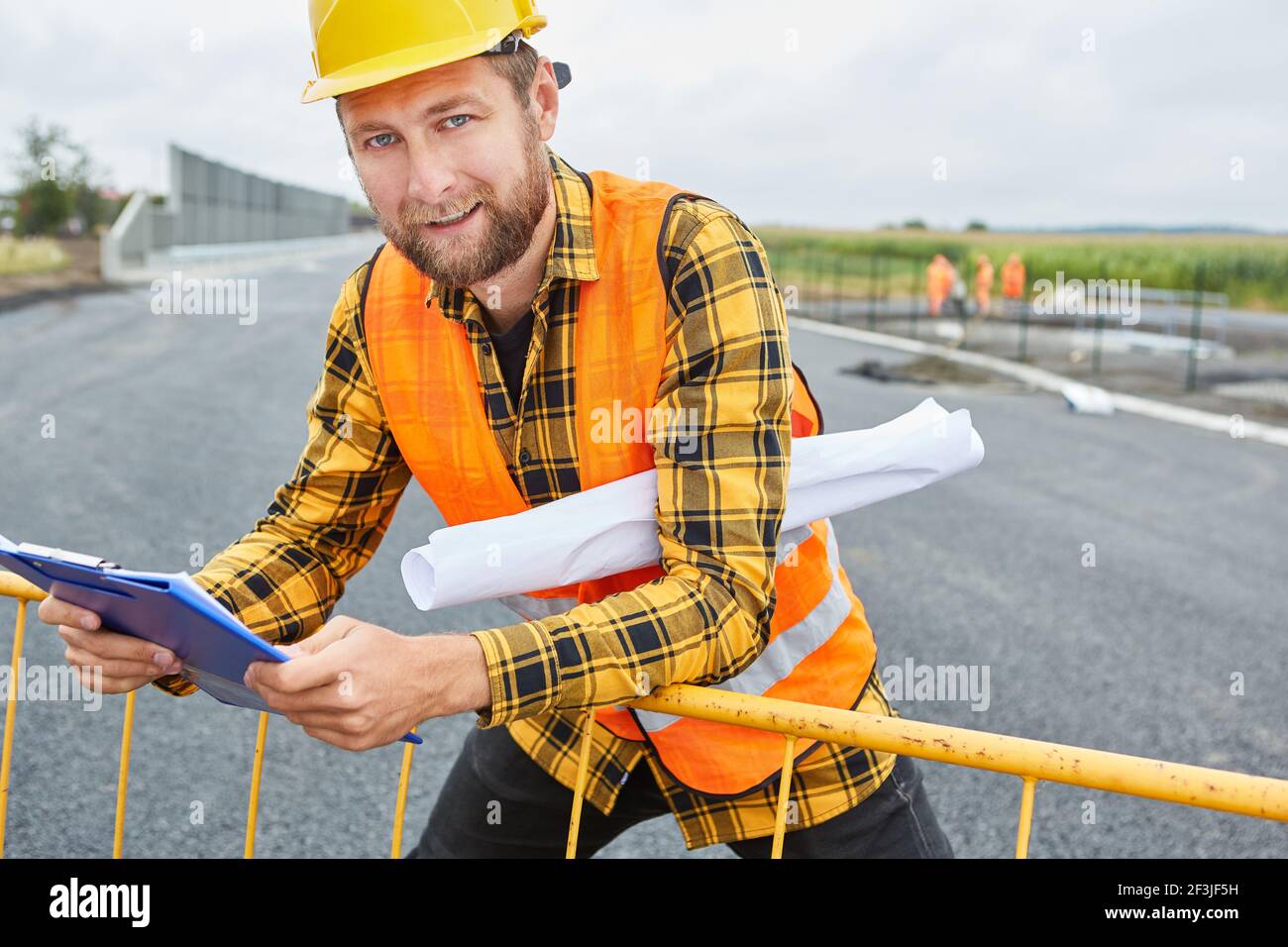 Workers as road builders with checklist and site plan on the road ...