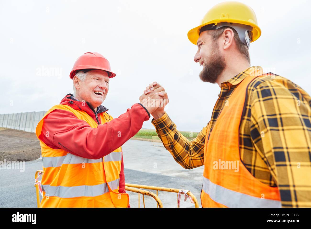 Architect and construction workers greet each other with a handshake on ...
