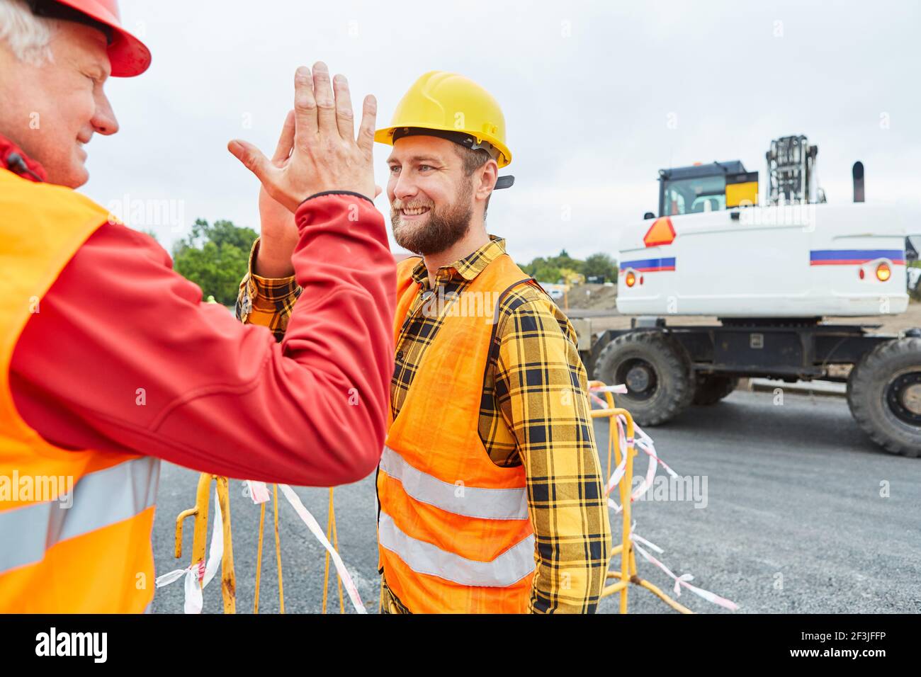 Two construction workers give each other a high five on the ...