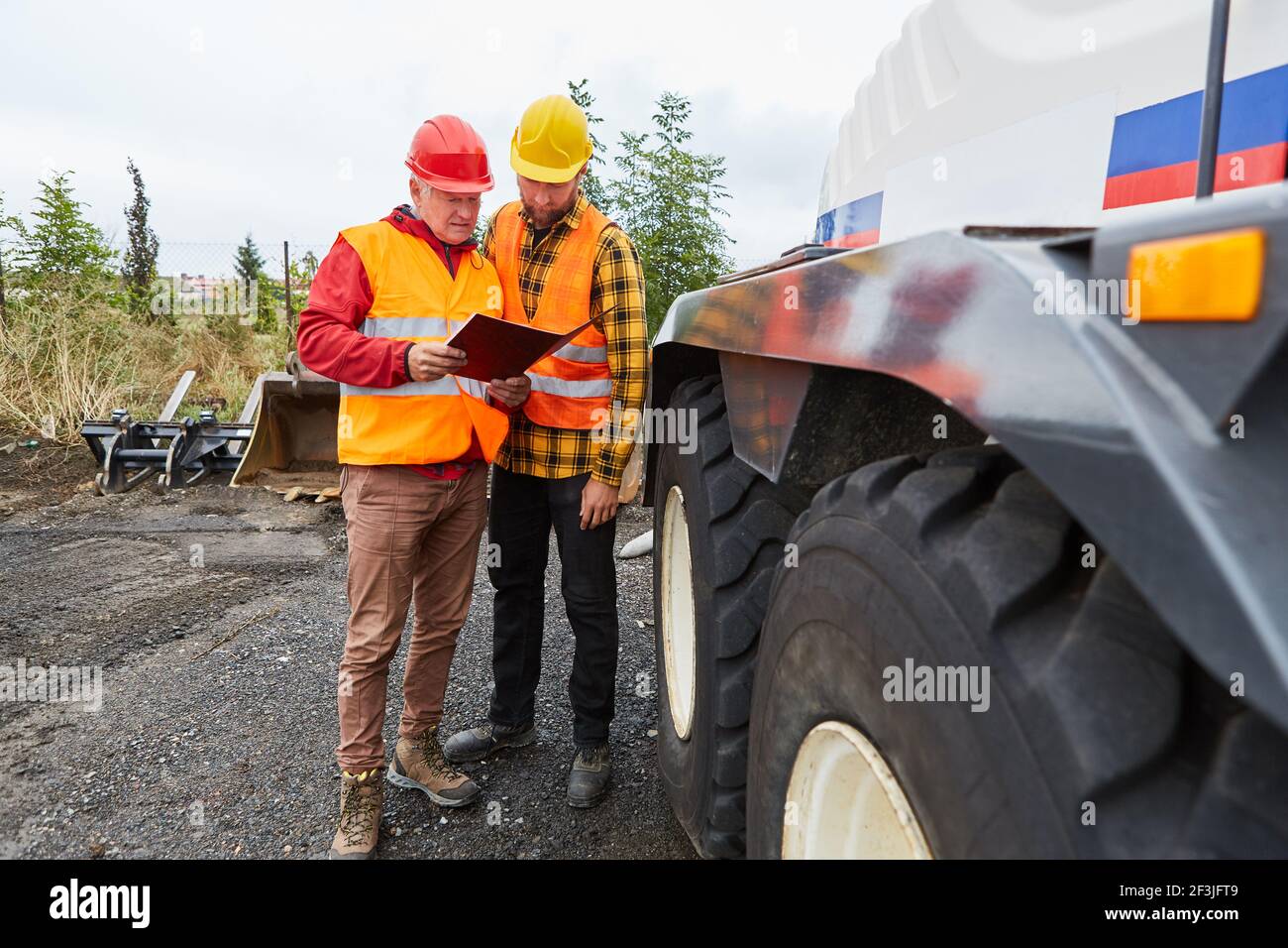 Site managers and construction workers next to a wheel loader check ...