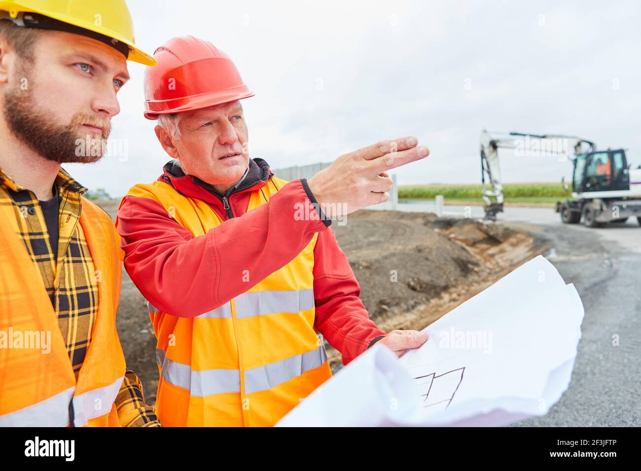 Construction manager and foreman with construction drawing on ...