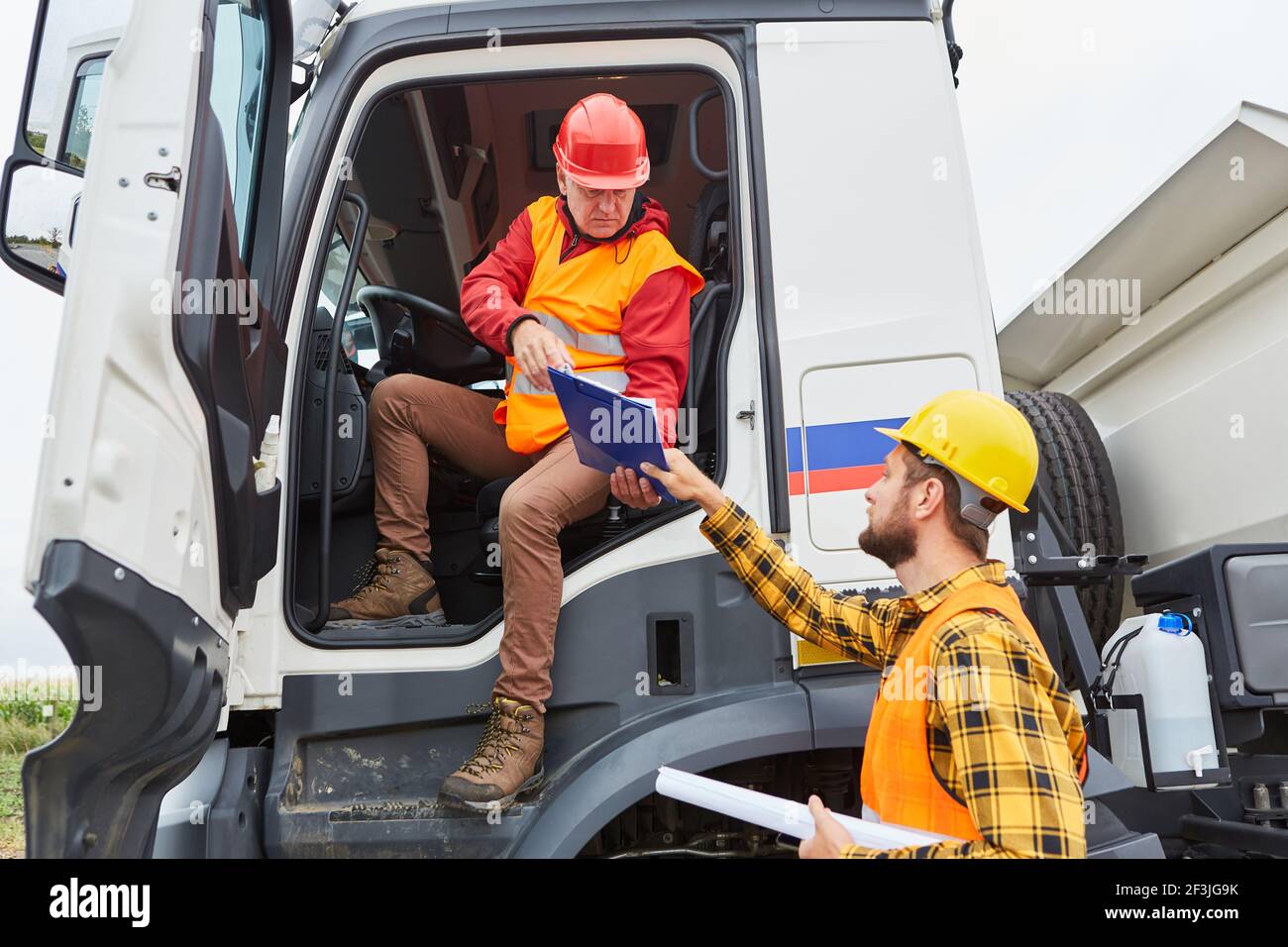 Truck driver brings delivery to construction site from road ...