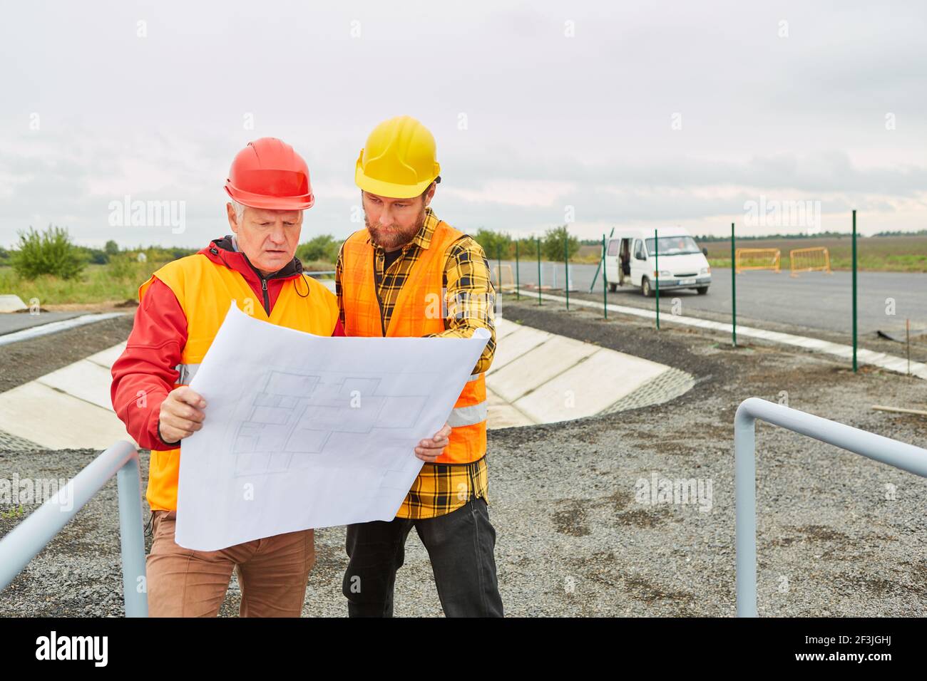 Architect and construction worker look at construction drawing on the ...
