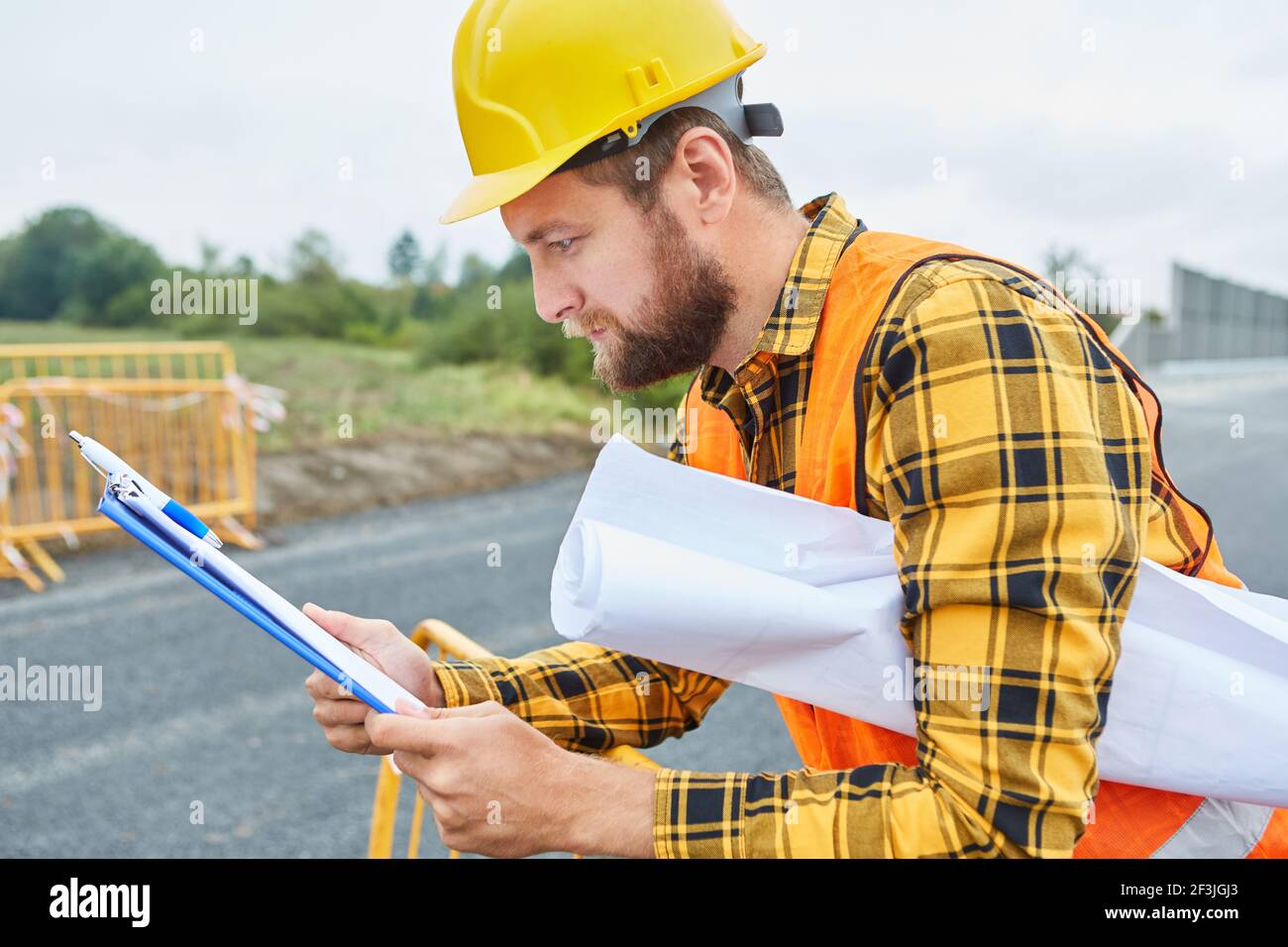 Construction worker as foreman with checklist and blueprint on the ...