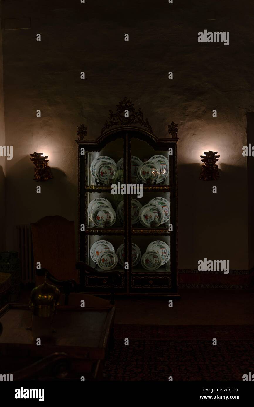 A vertical shot of an ancient cupboard with vintage plates in Palacio ...