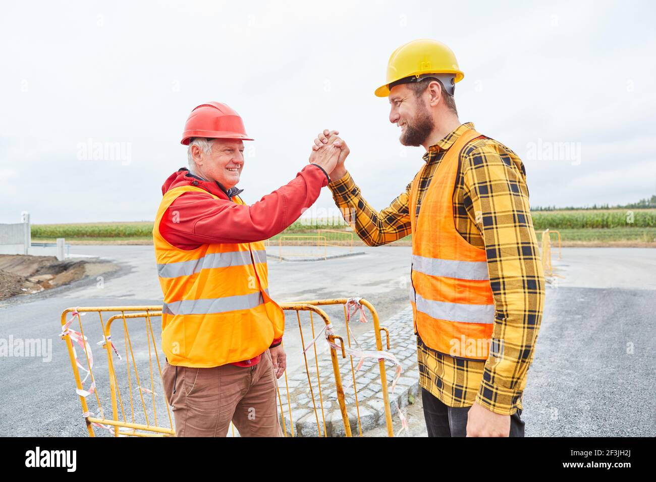 Two construction workers greet each other with a handshake at the ...