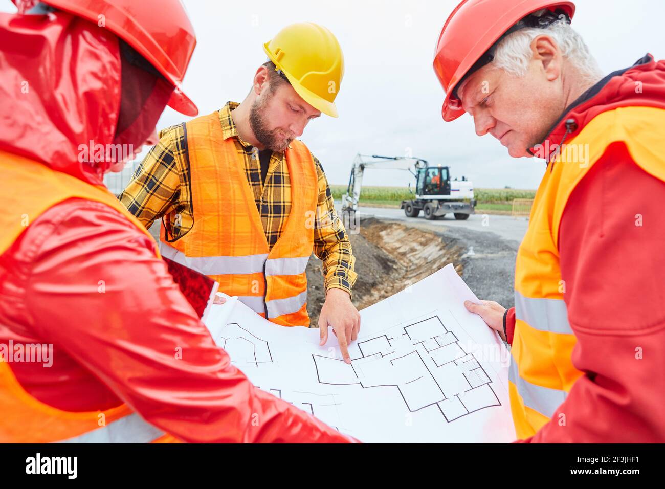 Three construction workers discuss construction plan on the ...