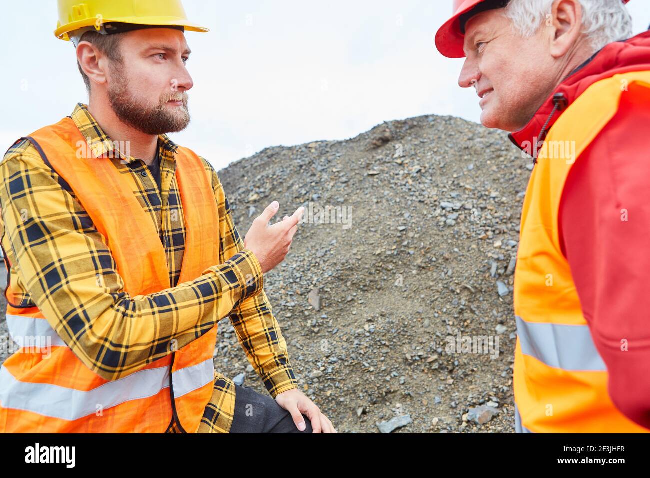Construction workers and architect in front of a mound of earth as ...