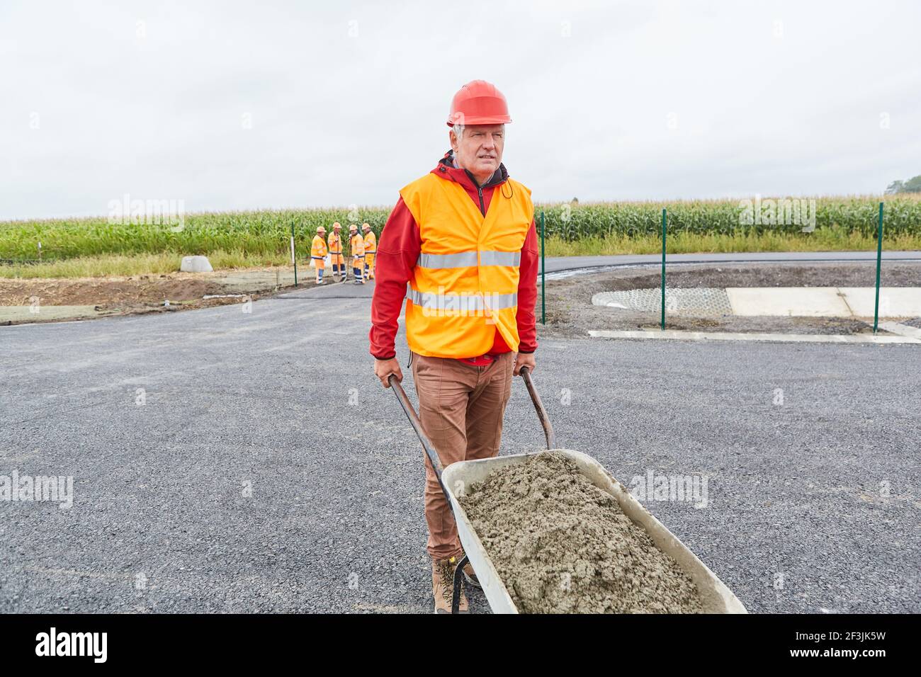 Construction worker pushes concrete in a wheelbarrow on construction ...