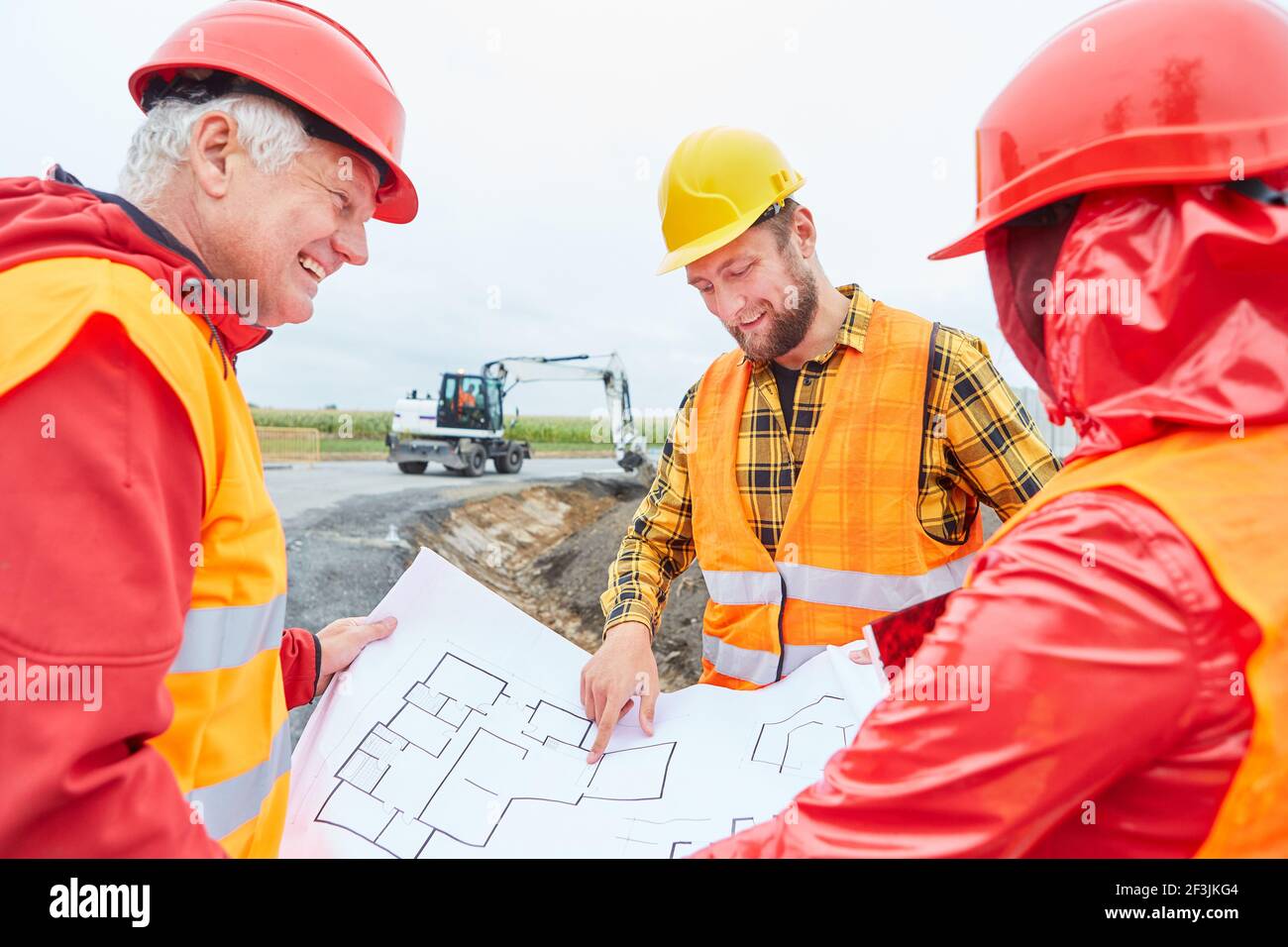 Construction workers team with floor plan during house construction ...