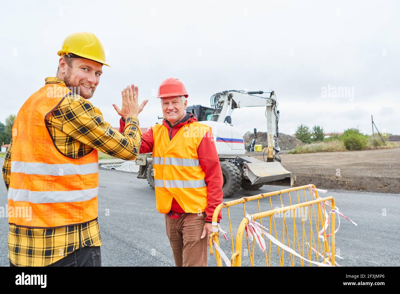 Two construction workers greet each other with high five at the road ...