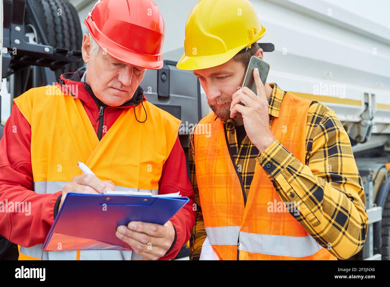 Construction manager and foreman with checklist and smartphone check a ...