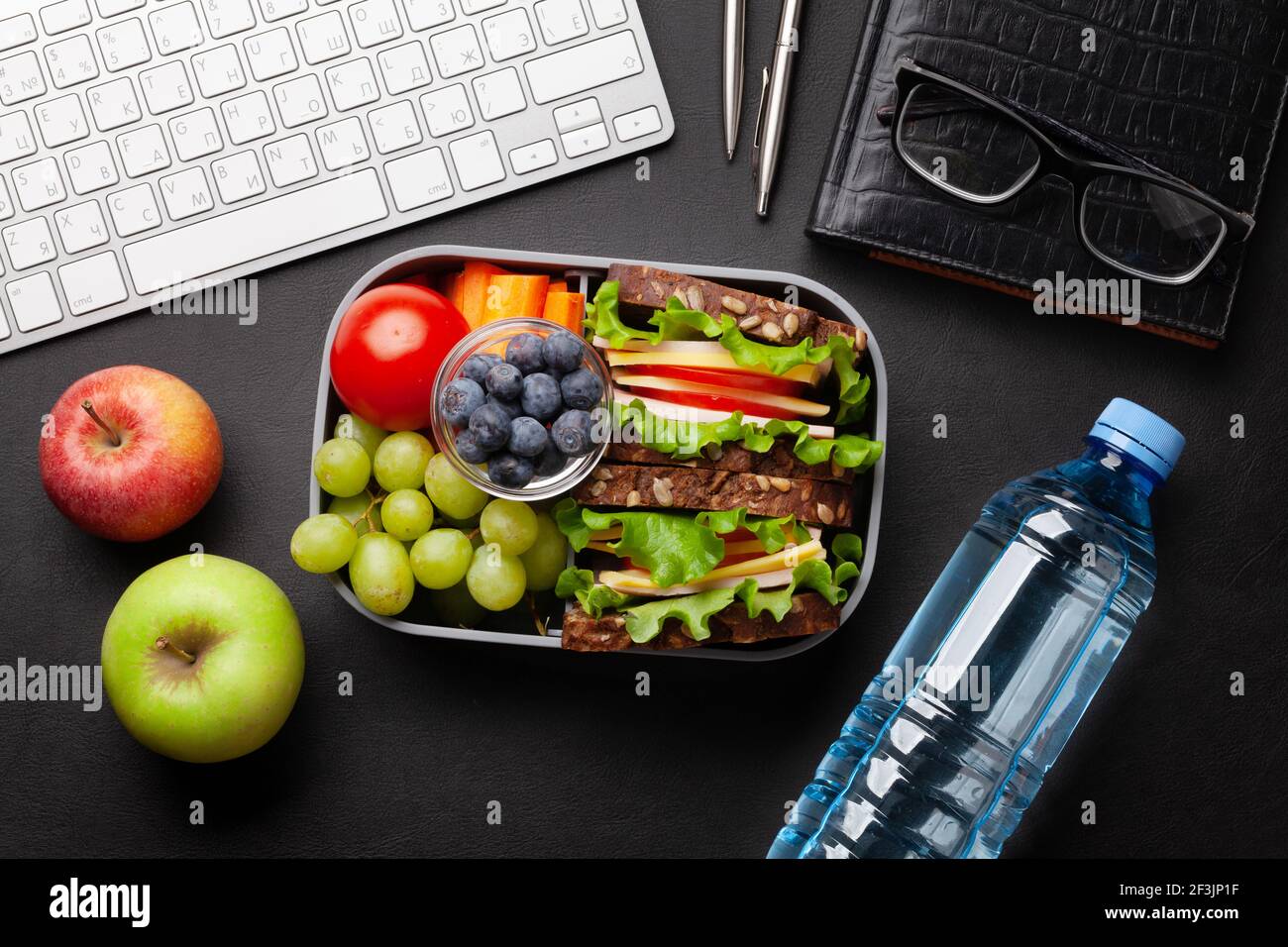 Healthy office lunch box with sandwich and fresh vegetables, water ...