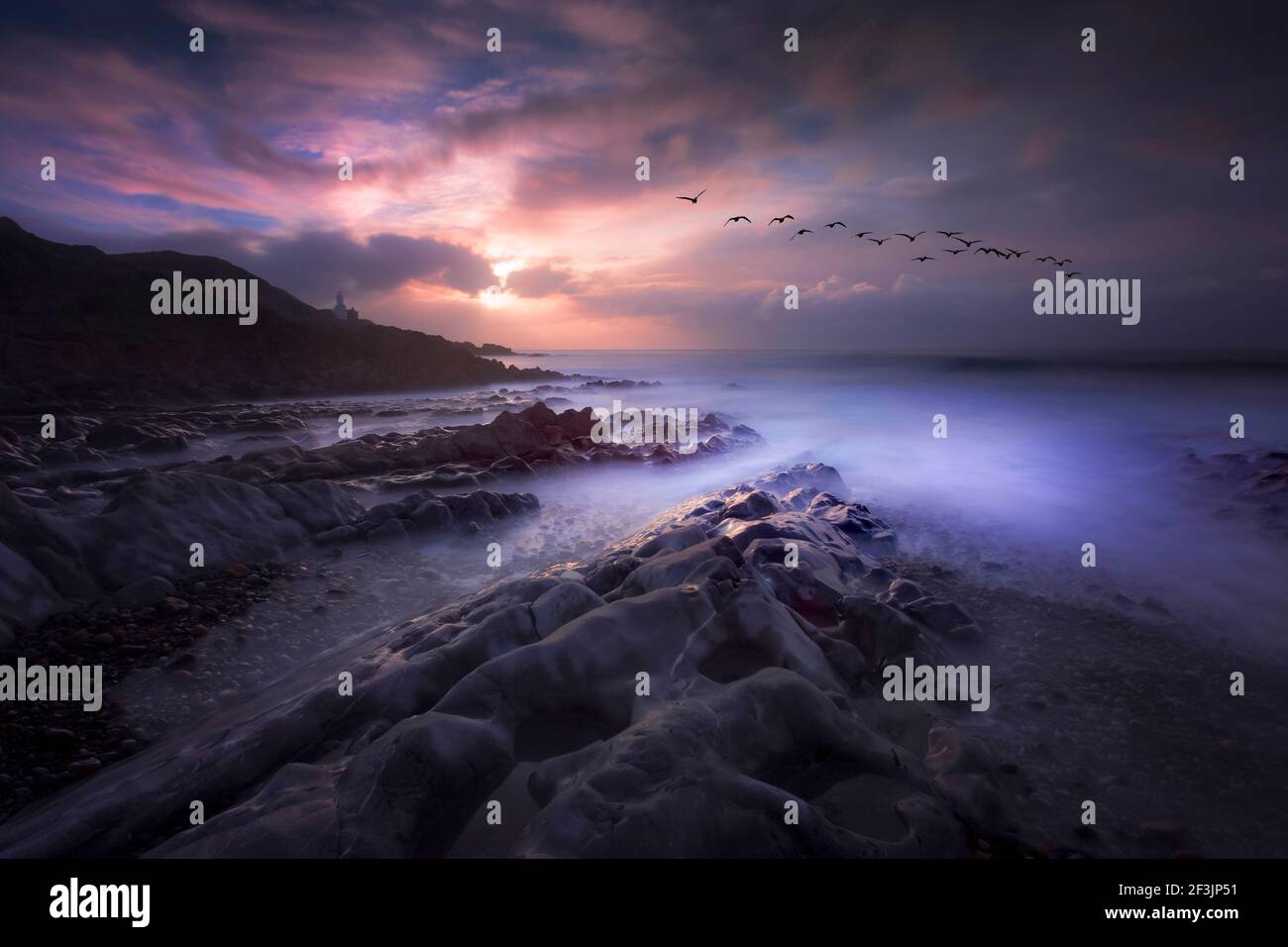 Birds fly at daybreak over the rock pools at Bracelet Bay on the Gower ...