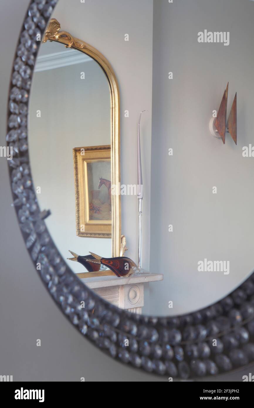 Double reflection. Gilt mirror over fireplace reflected in circular ...