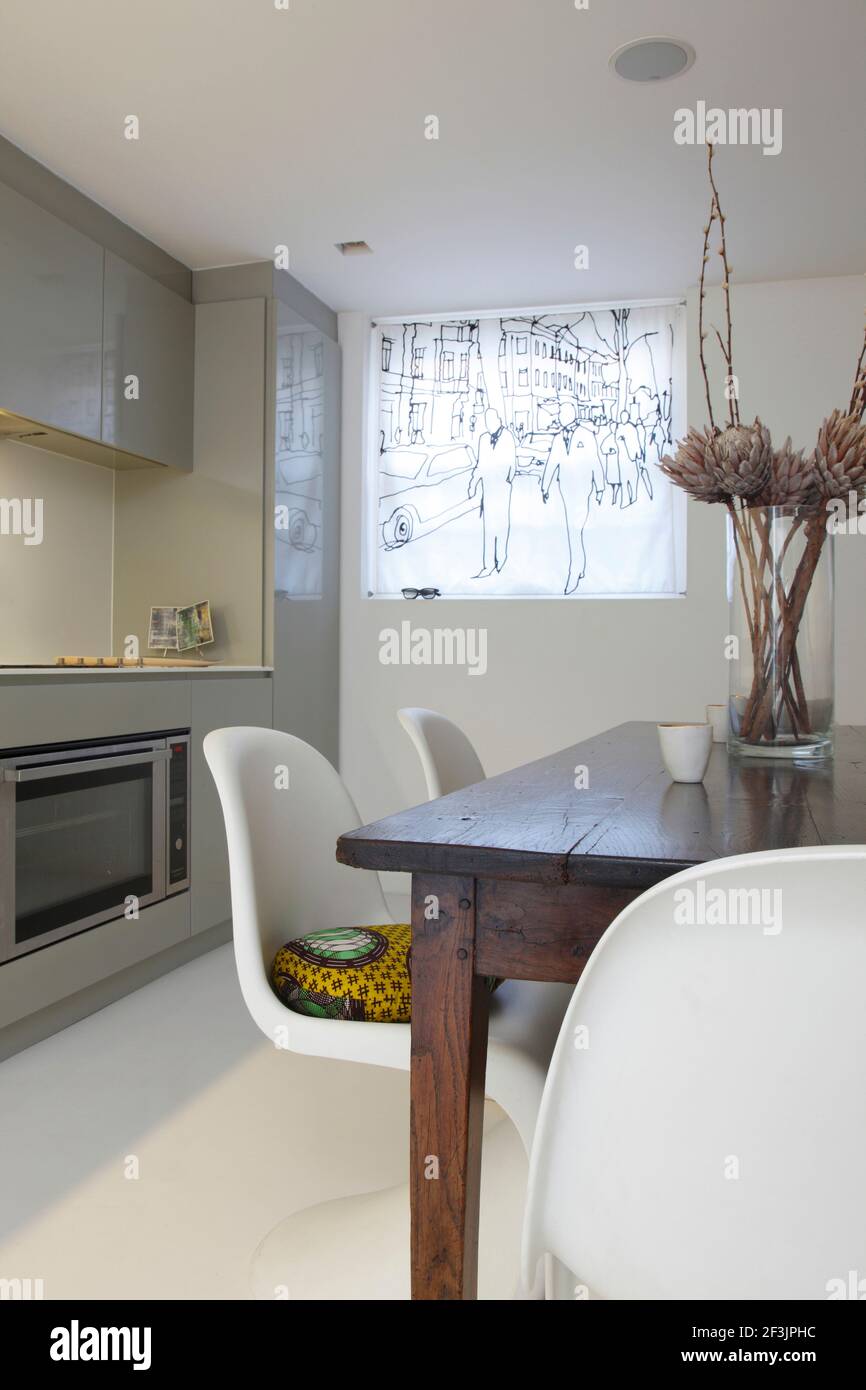 White Verner panton chairs around a rustic French table in basement ...