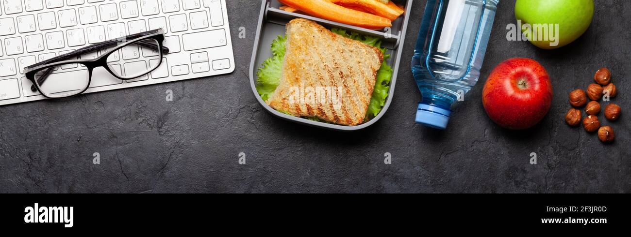 Healthy lunch box with sandwich, water bottle and fruits on office ...