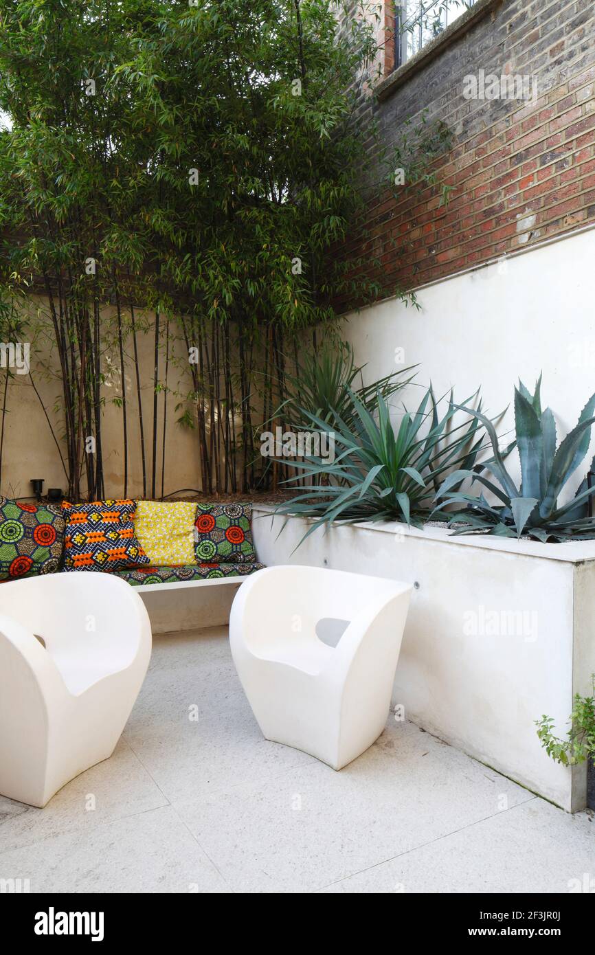 Pair of Ron Arad garden chairs in front of bench with tribal print ...