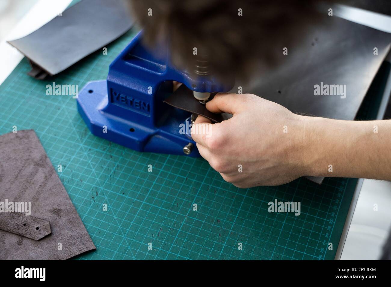 Artisan using hand press for setting snaps in leather for makes a ...