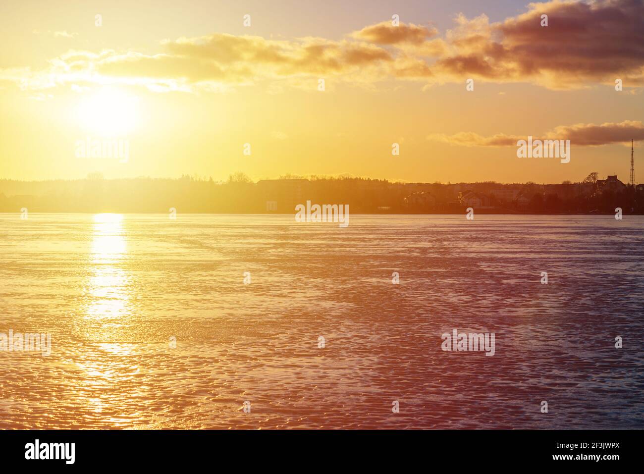 Winter landscape with frozen lake at sunrise or sunset. Lake glistening ...