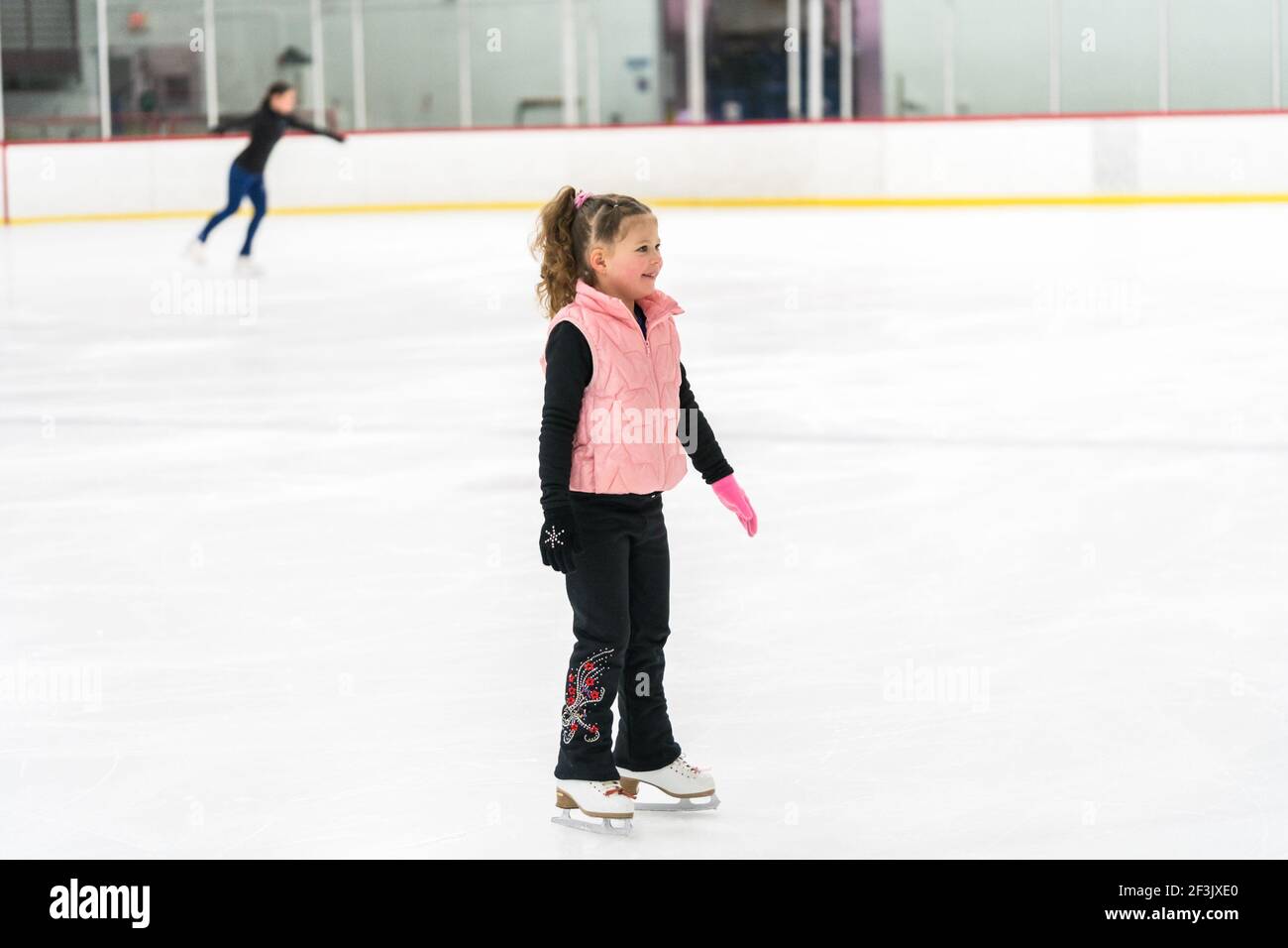 Little girl practicing figure skating elements on indoor ice skating ...