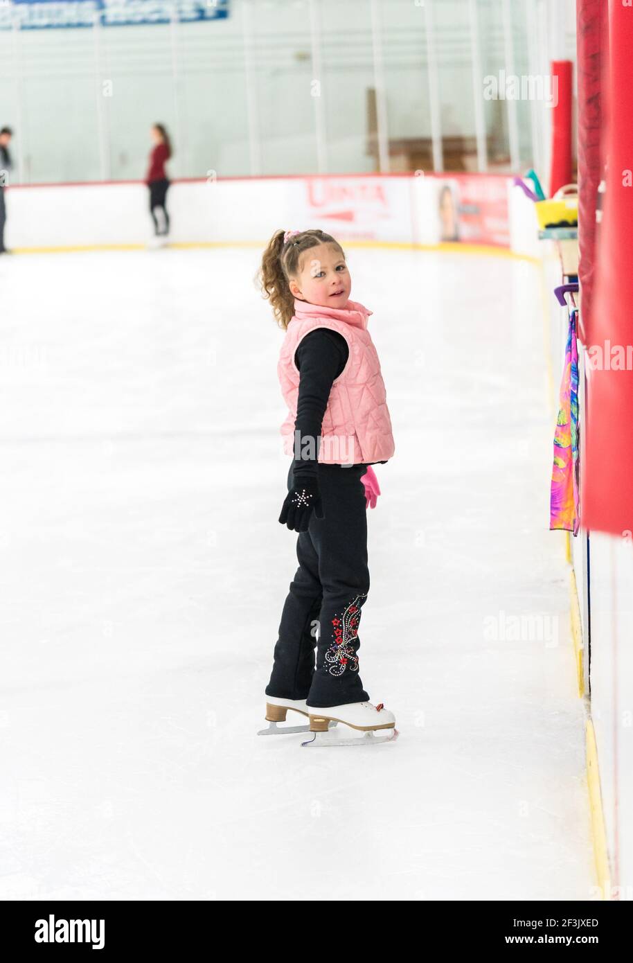 Little girl practicing figure skating elements on indoor ice skating ...