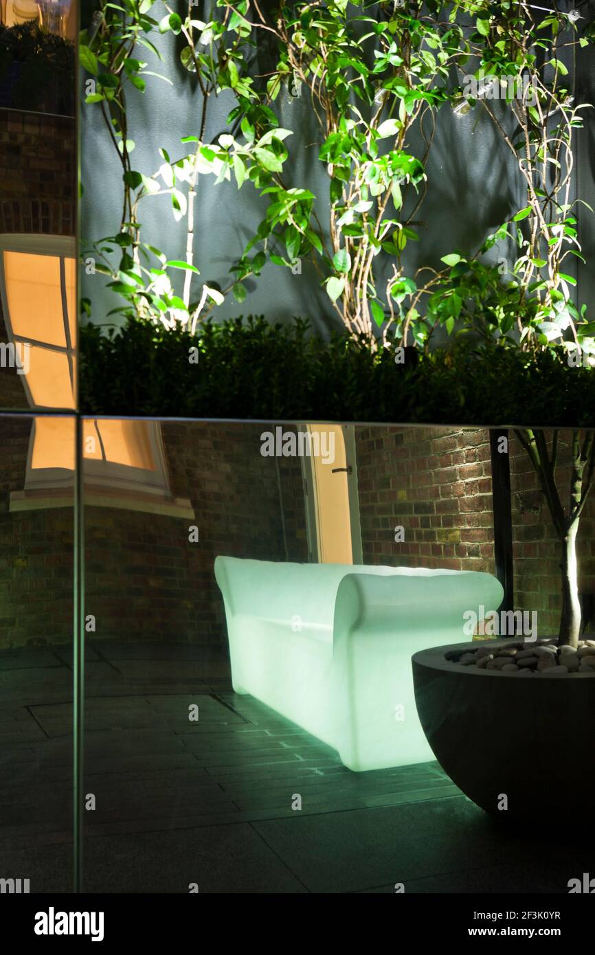 Reflection of the self-illuminating sofa in the reflective metal wall ...