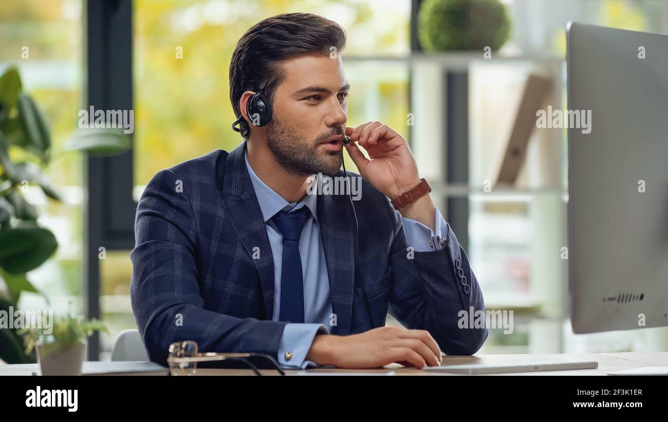 bearded operator talking in microphone while looking at computer ...