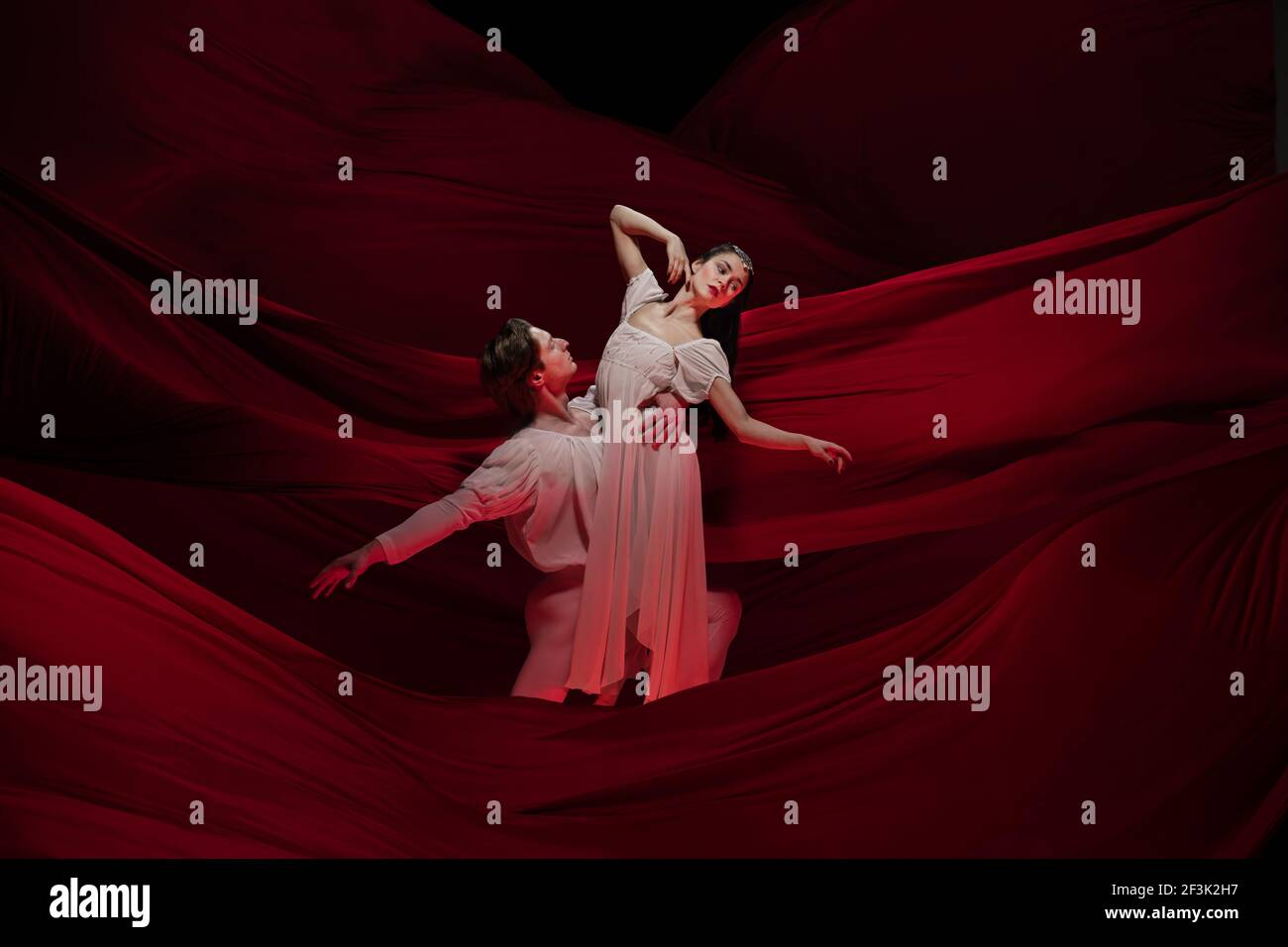 Passionate. Young and graceful ballet dancers on red cloth background ...