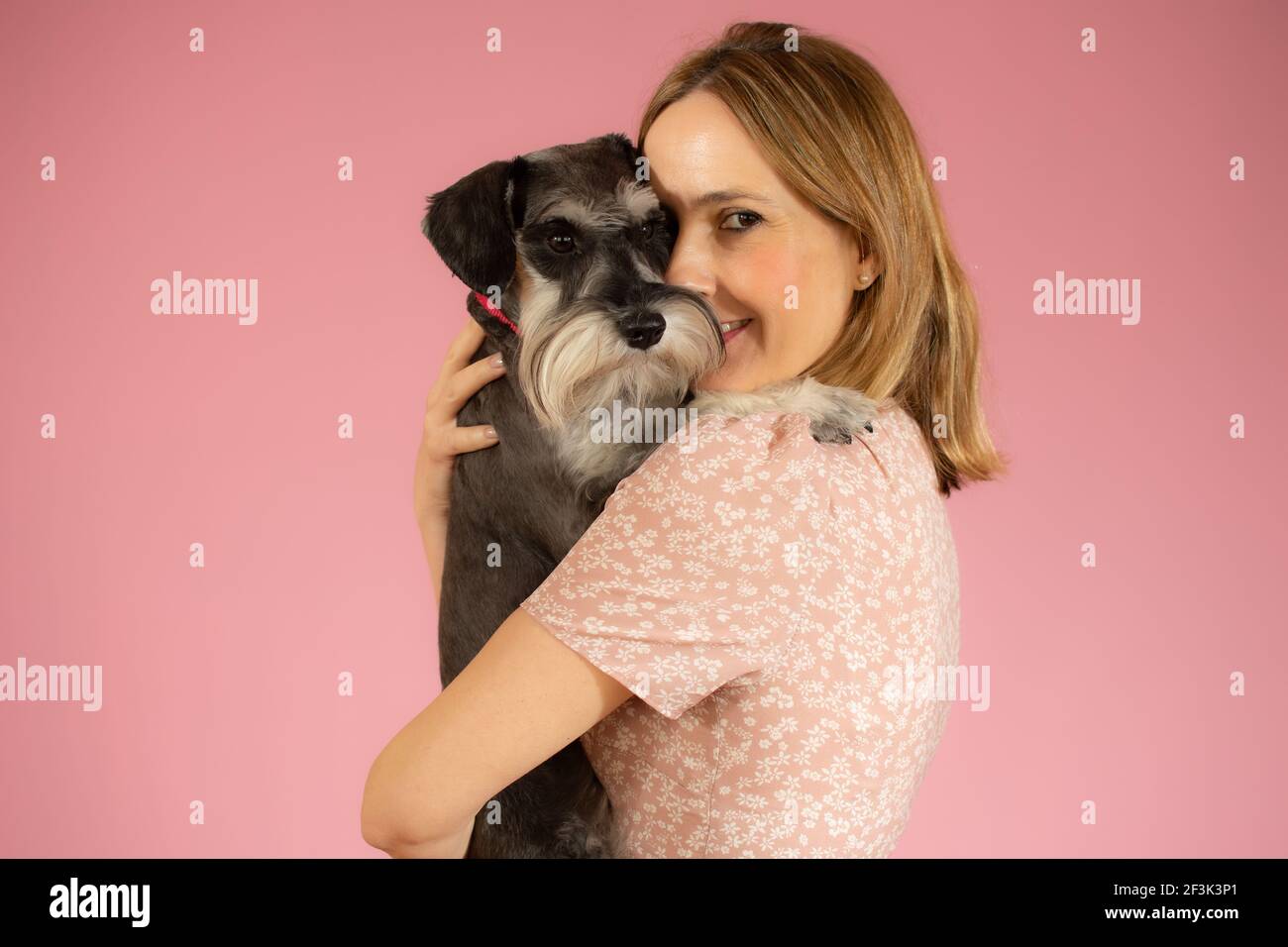 Cute young woman hugs her puppy schnauzer dog. Love between owner and ...