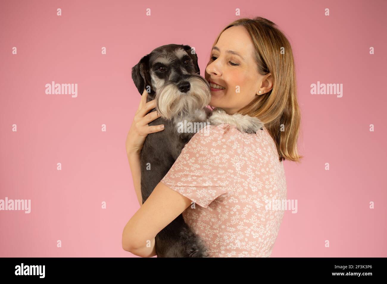 Cute young woman hugs her puppy schnauzer dog. Love between owner and ...