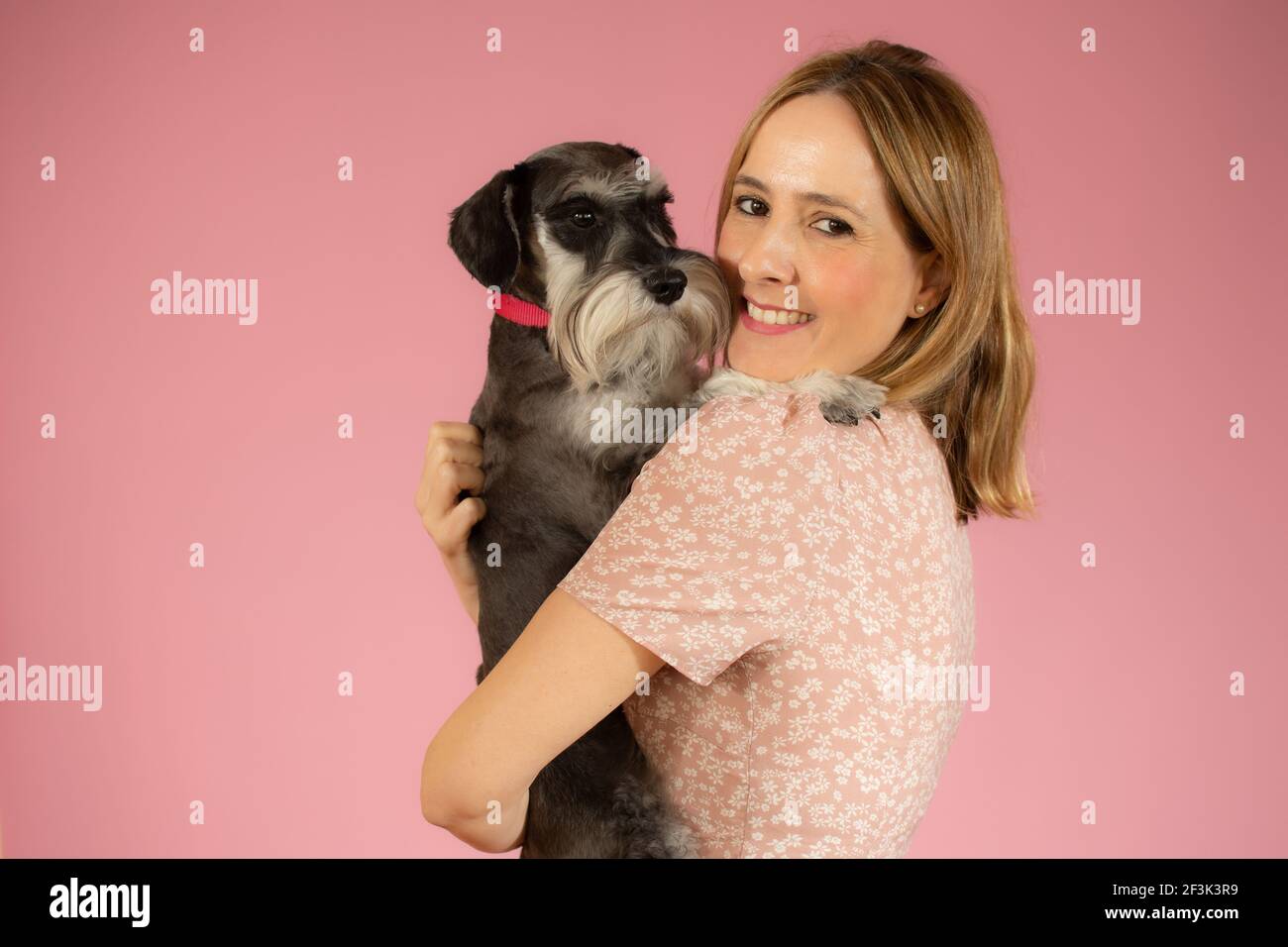 Cute young woman hugs her puppy schnauzer dog. Love between owner and ...
