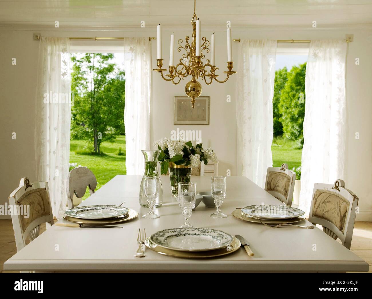 Dining room table set for three with view through windows to back ...