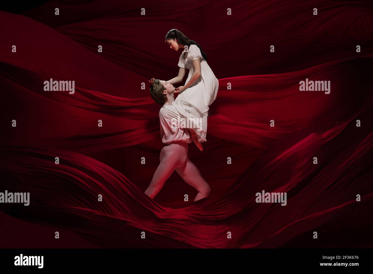 Wine. Young and graceful ballet dancers on red cloth background in ...