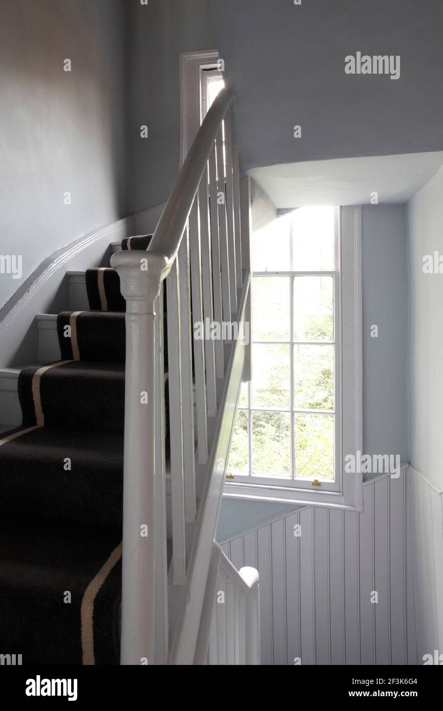 Pale blue and grey stairwell with t&g panelling and dark carpet ...