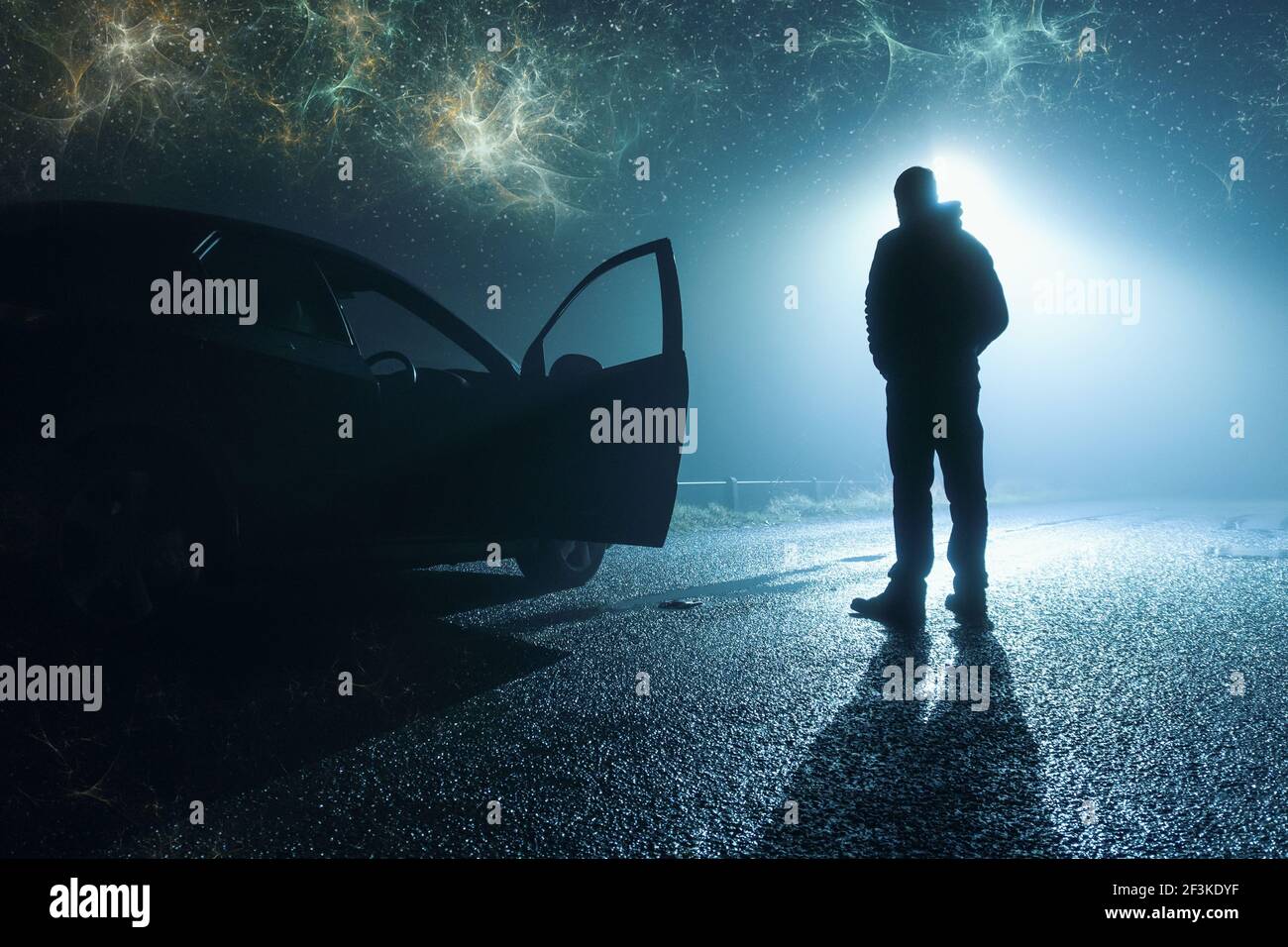 A man next to a car parked on the side of the road, underneath a street ...