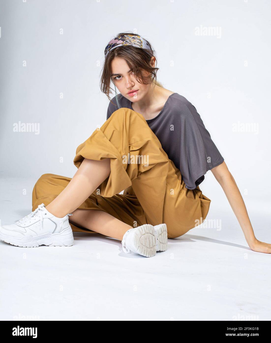 White european young girl on light grey with crossed legs Stock Photo ...
