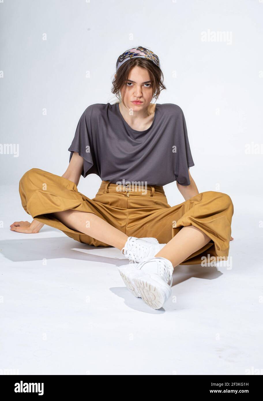 White european young girl on light grey sitting on the floor with ...