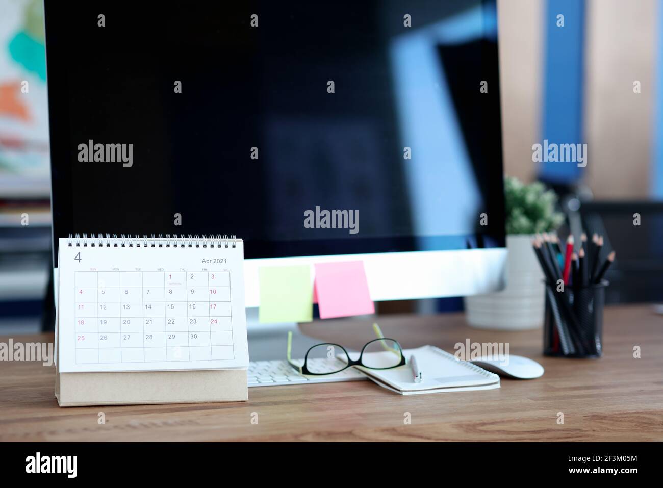 Loose leaf paper calendar standing near computer on desktop closeup ...
