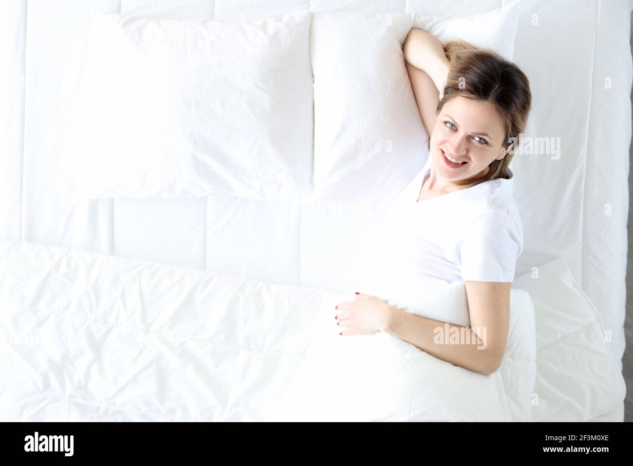 Young woman lying in bed and smiling top view Stock Photo - Alamy