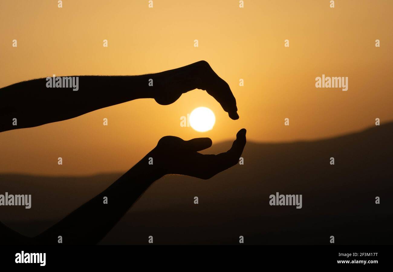 Two hands holding the sun at sunset - perfect for the background or ...