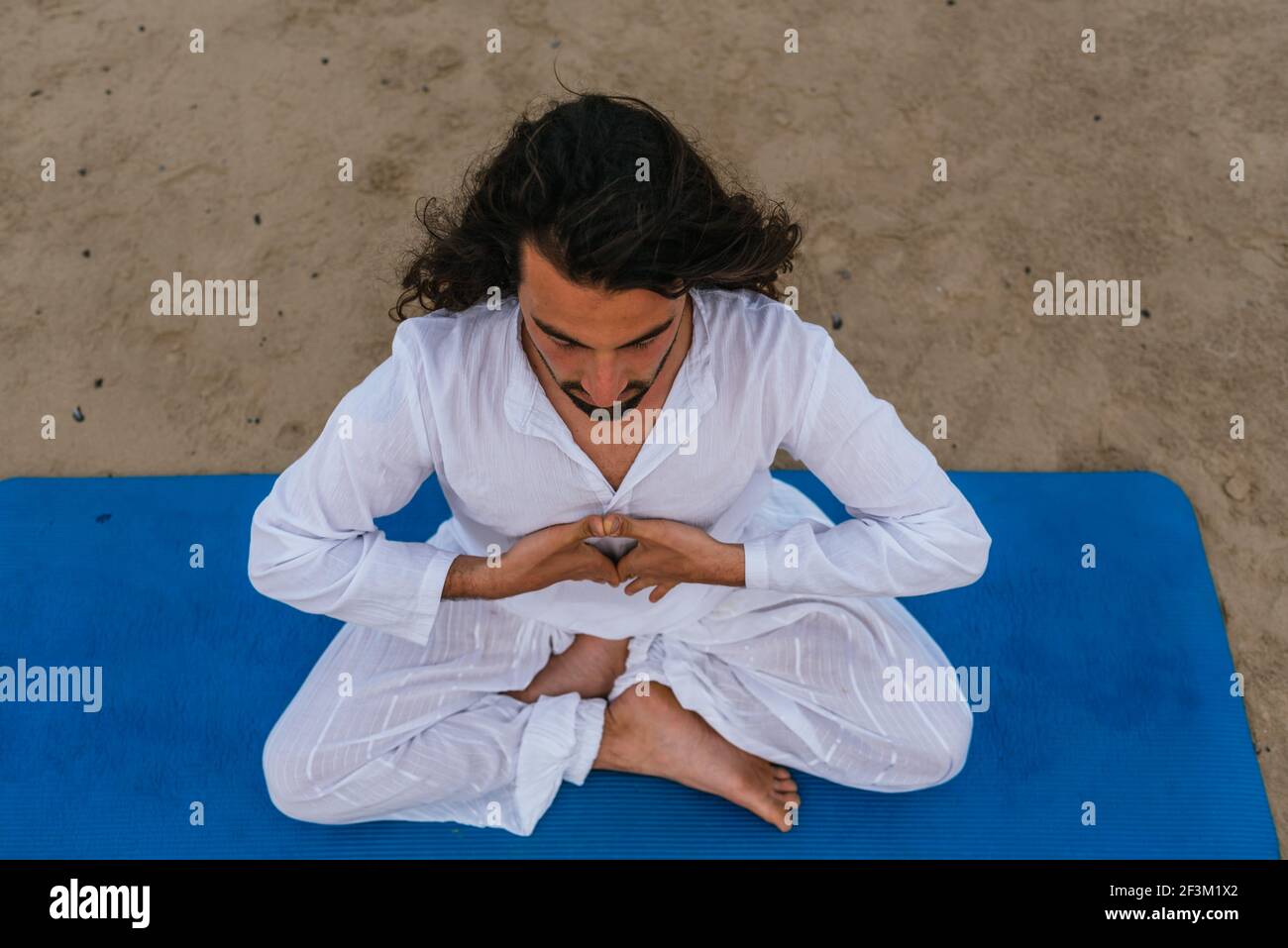 Stock photo of adult man with long hair doing yoga poses in the beach ...