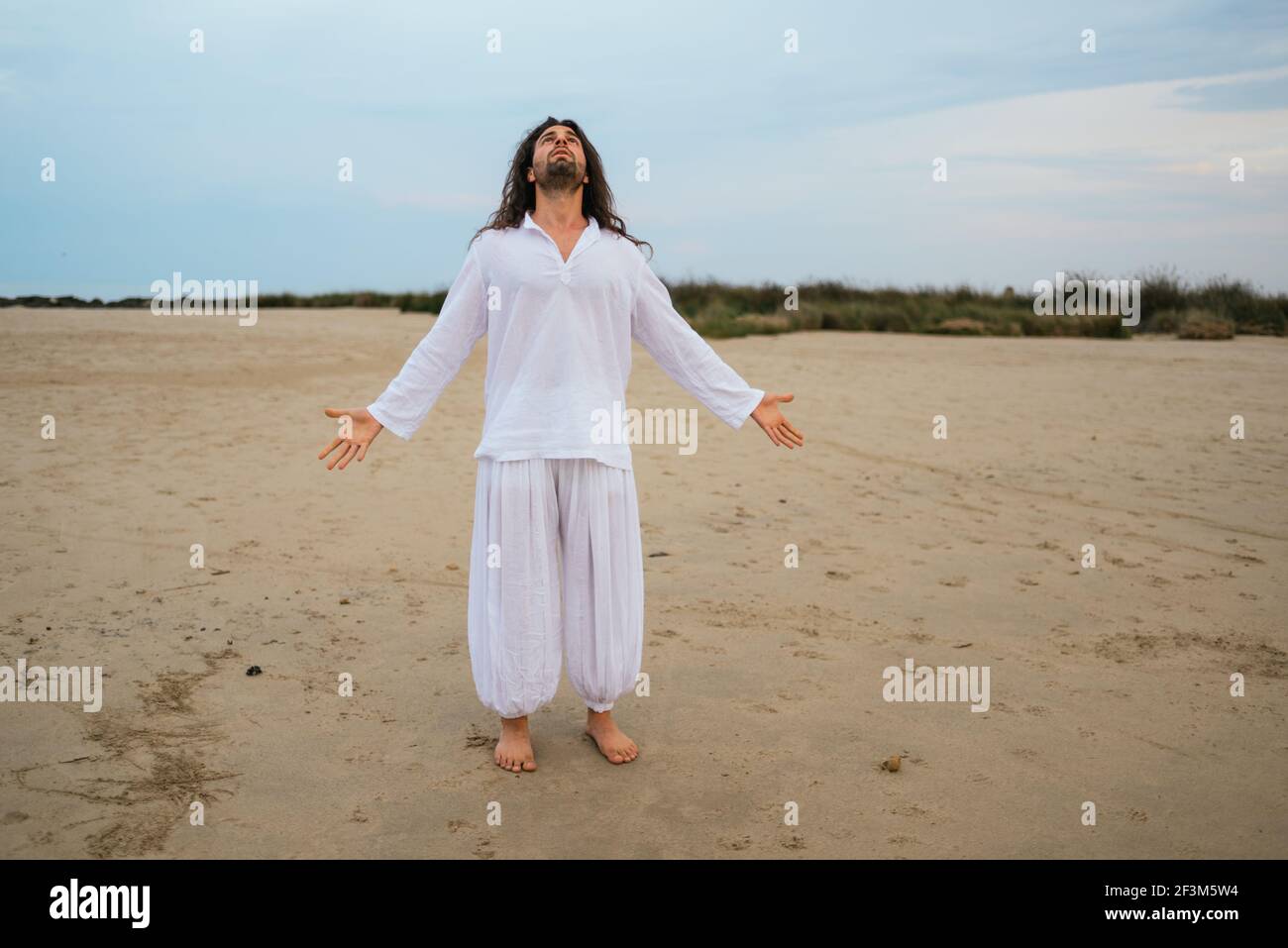 Stock photo of adult man with long hair asking for god in the beach ...
