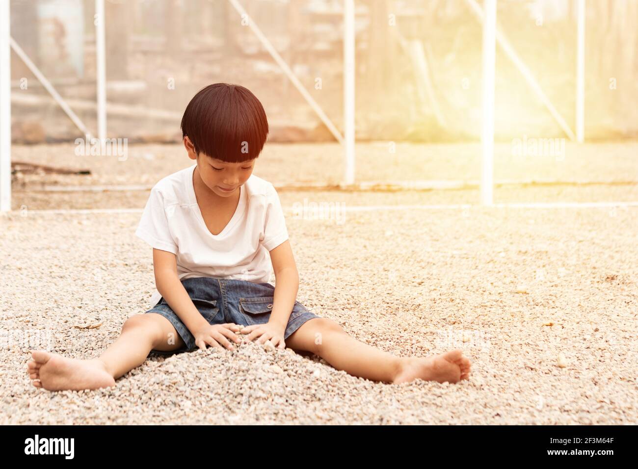 Adorable Asian little boy playing making gathering small stones ...