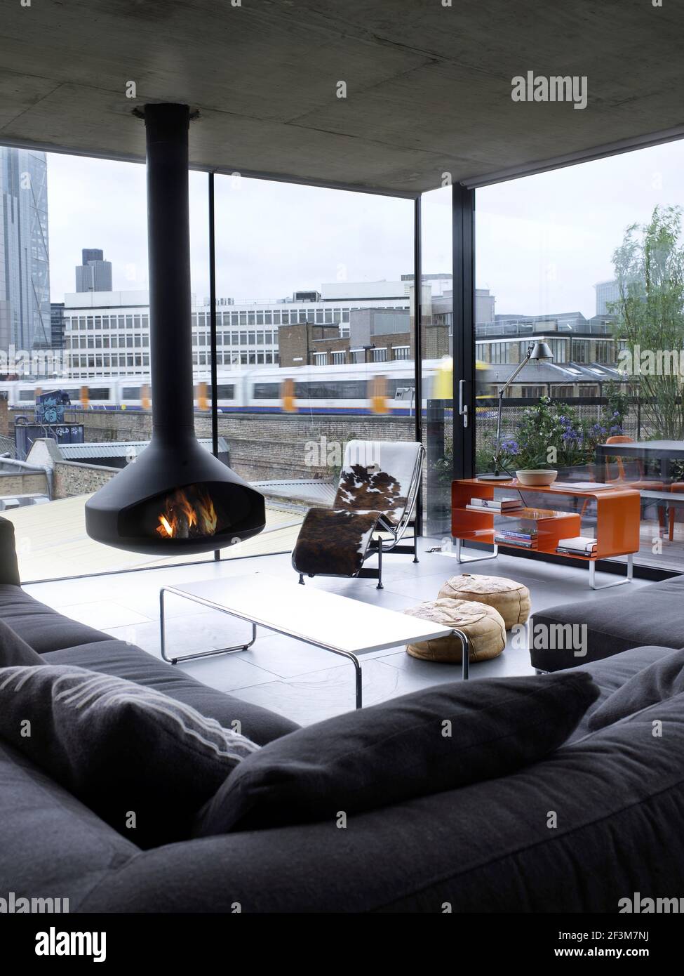Spacious open plan room with suspended fireplace and glass walls in ...
