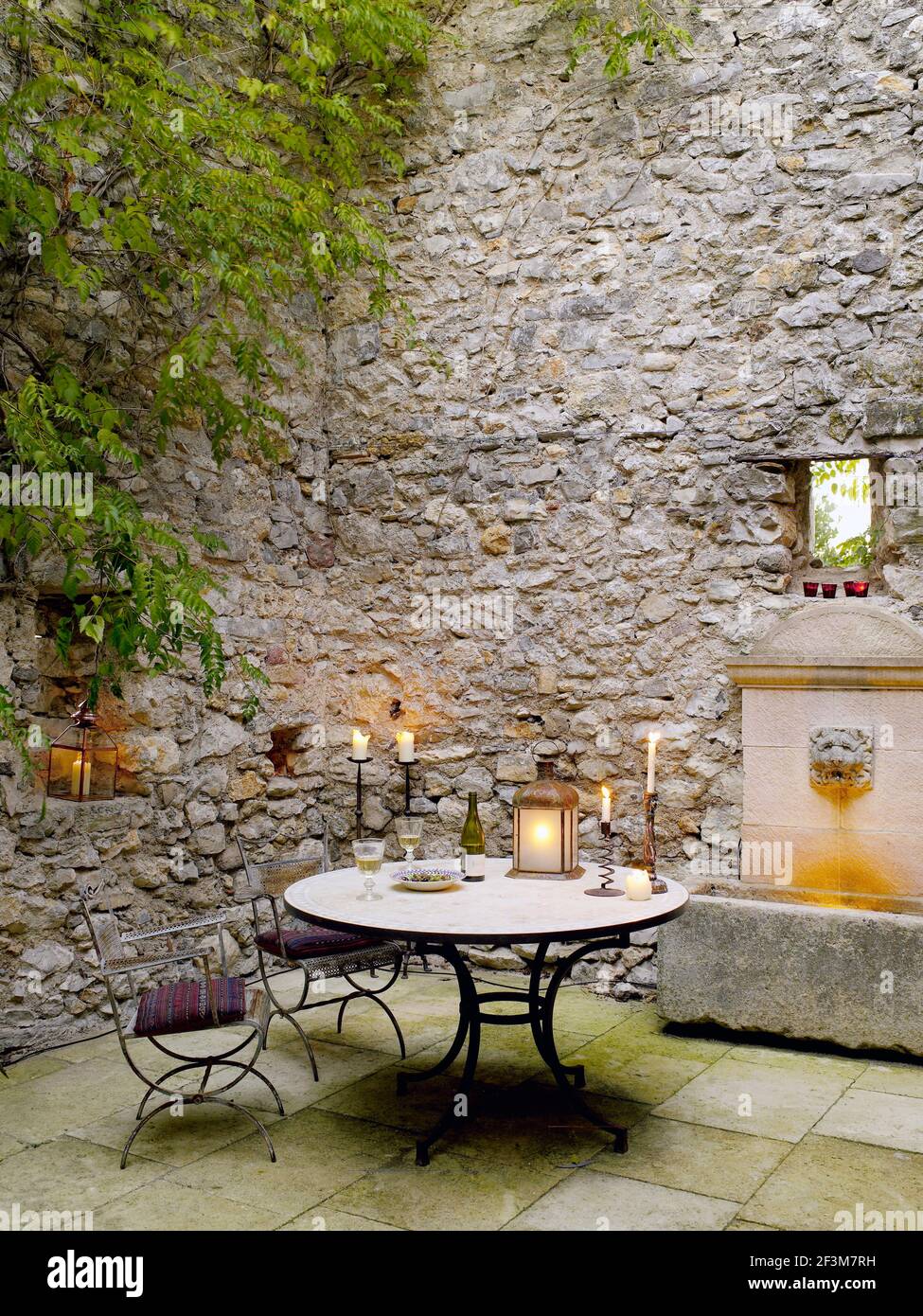 Small round table on patio surrounded by stone wall in courtyard of ...
